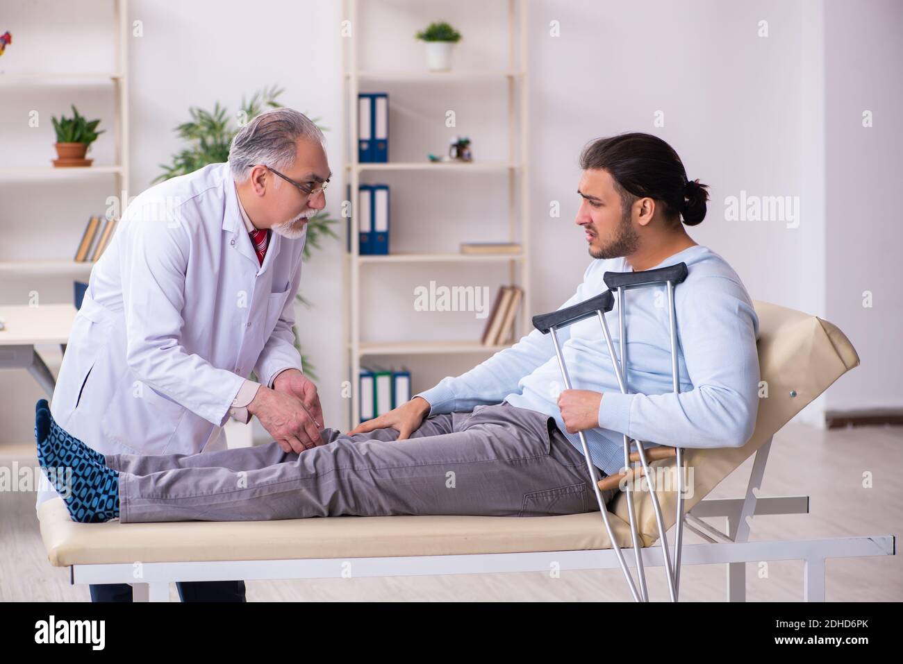 Young leg injured man visiting old doctor osteopath Stock Photo - Alamy