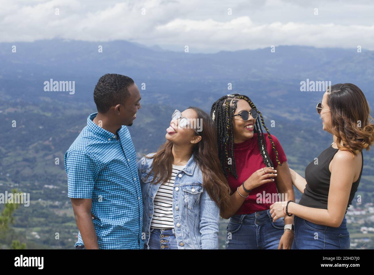 group of four Latin American adventurers friends outdoors smiling using ...