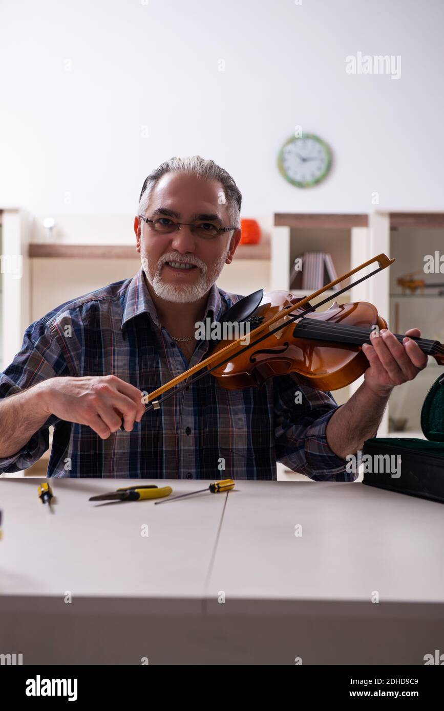 Senior male repairman repairing musical instruments at home Stock Photo ...
