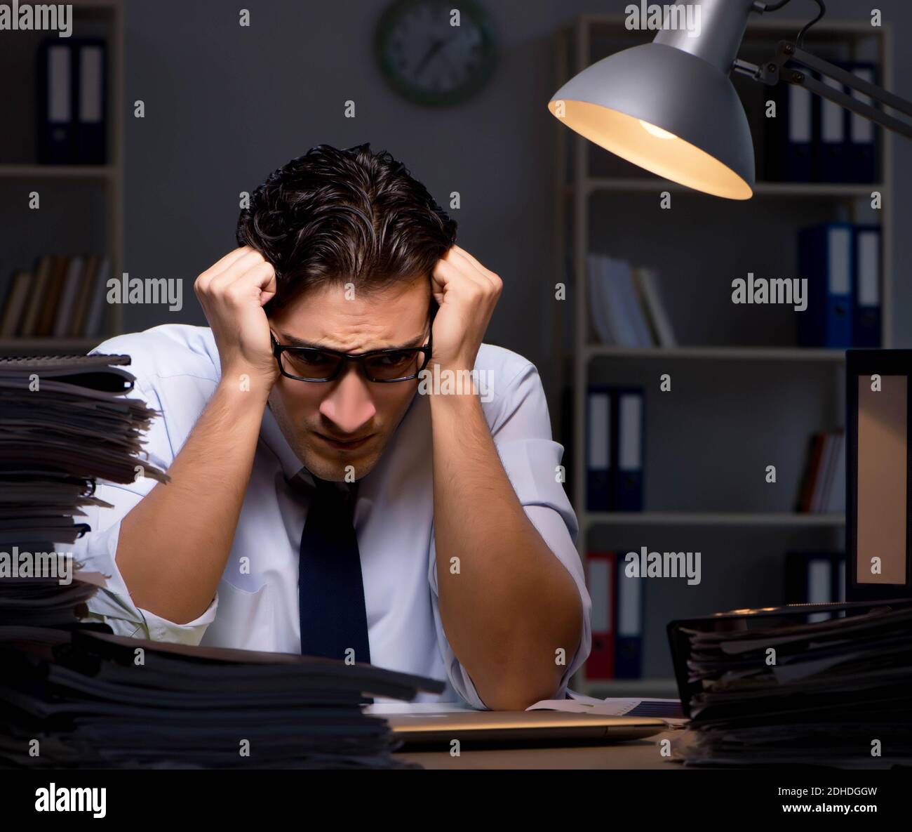 Young businessman working overtime late in office Stock Photo - Alamy