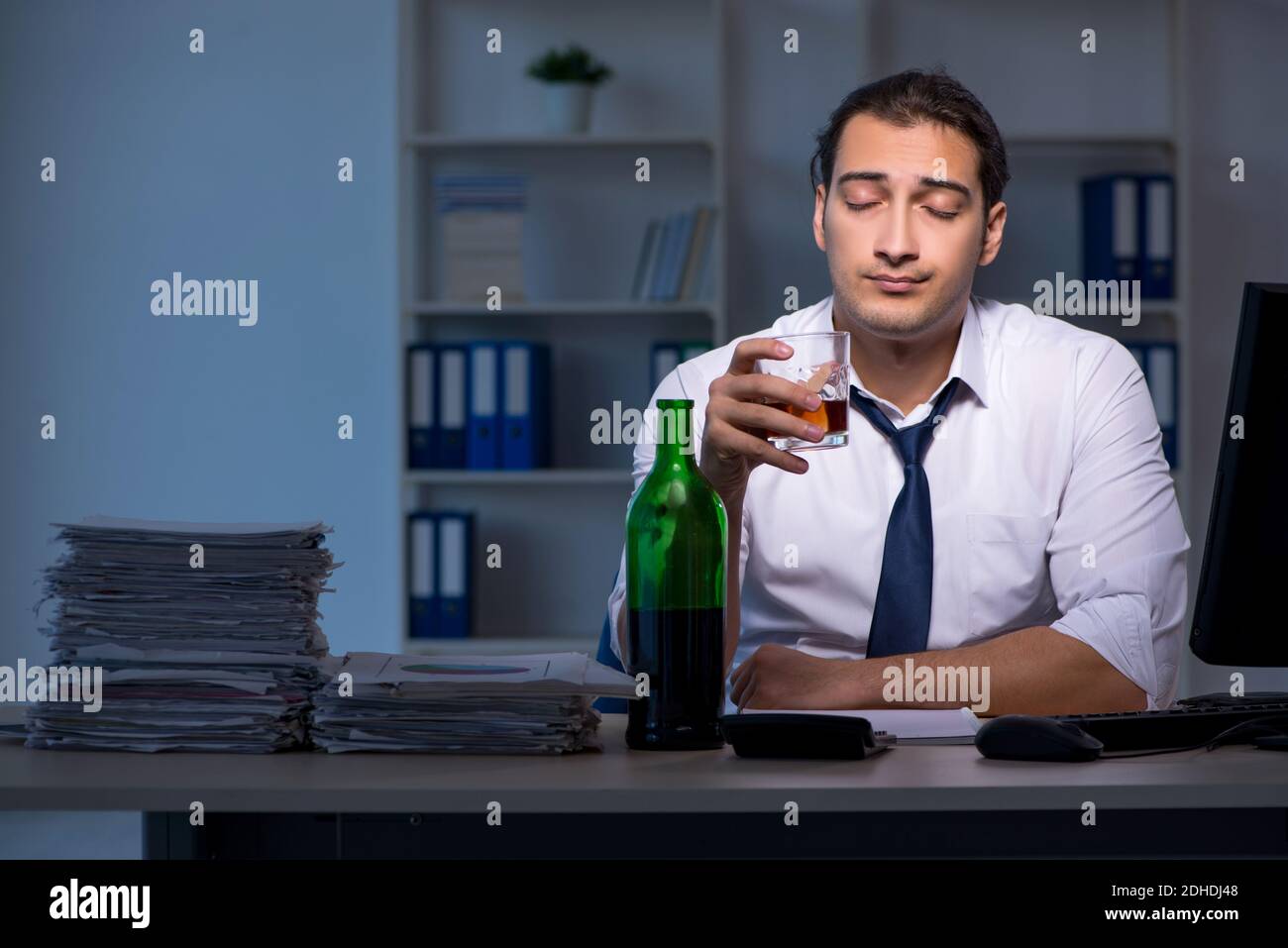 Alcohol addicted businessman working late in the office Stock Photo - Alamy