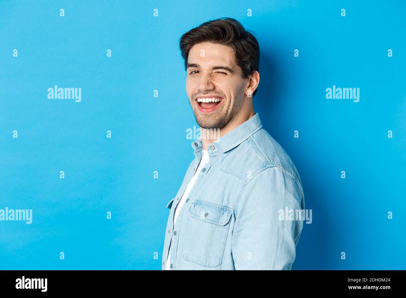 Happy and confident man turn head at camera, winking and smiling ...