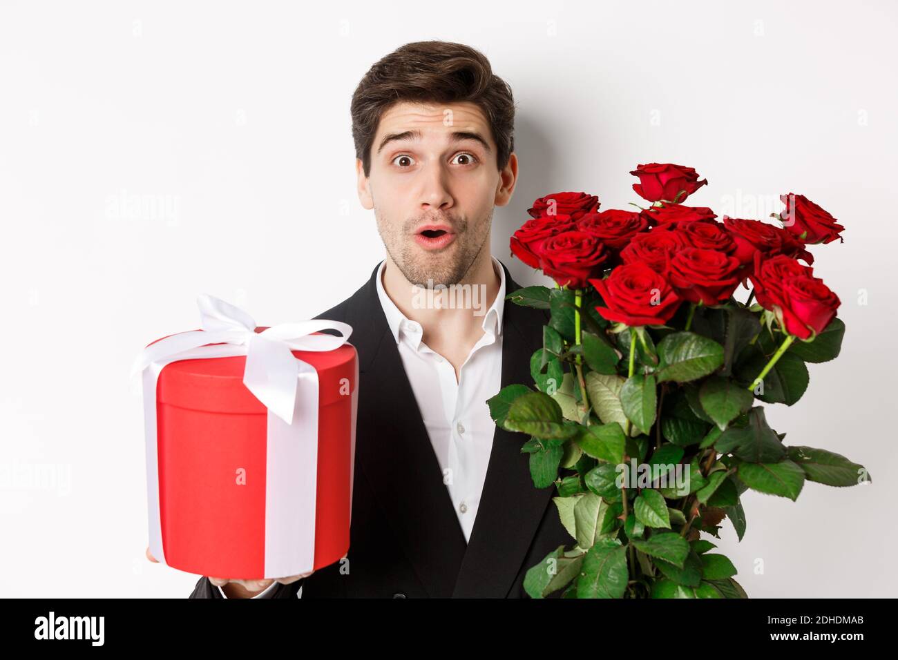 Close-up of attractive man in suit looking surprised, holding gift box ...