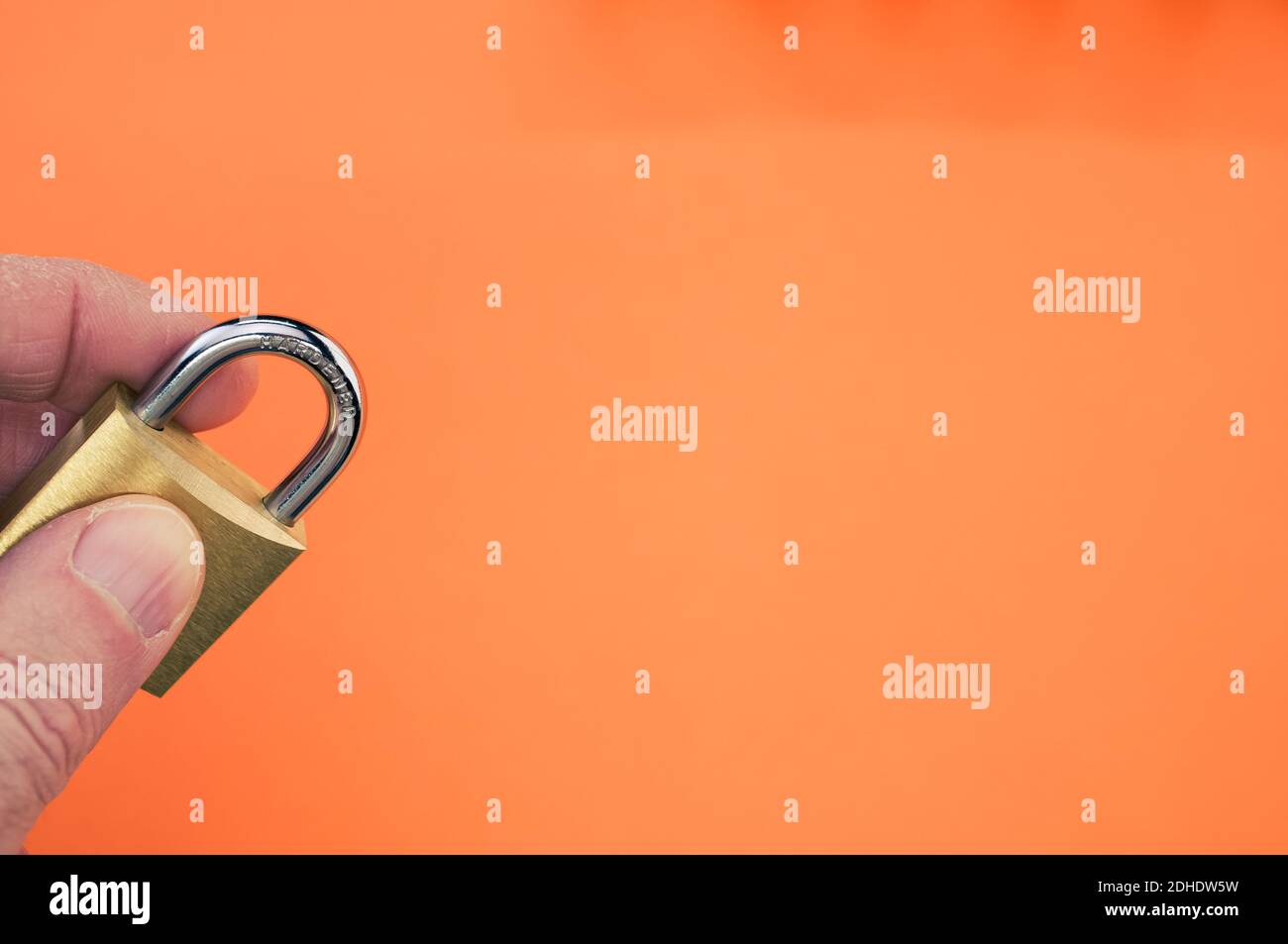 A closeup shot of a man's hand holding a padlock over an orange ...