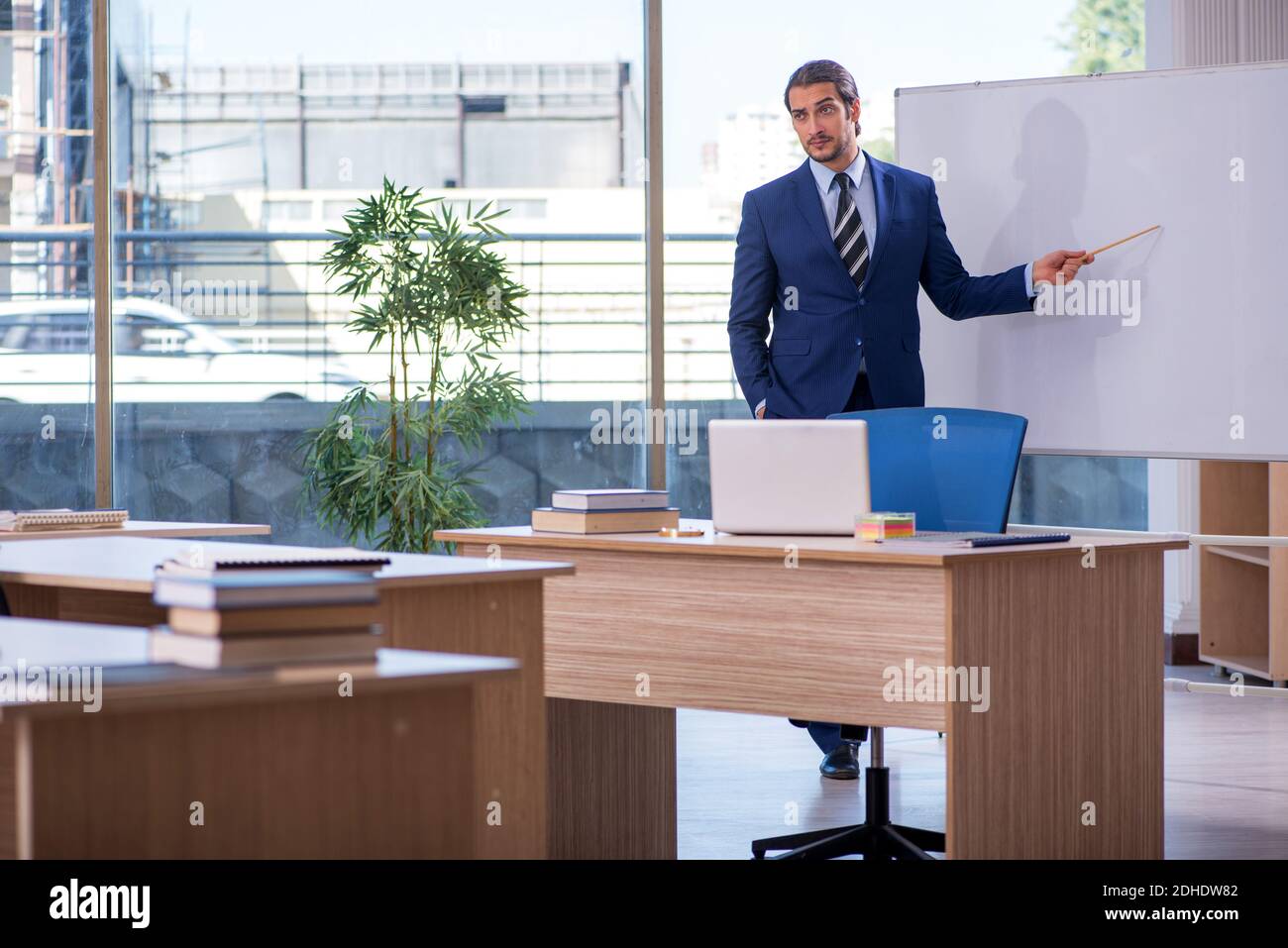 Young male teacher in suit in the classroom Stock Photo - Alamy