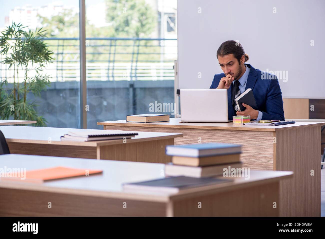 Young male teacher in suit in the classroom Stock Photo - Alamy