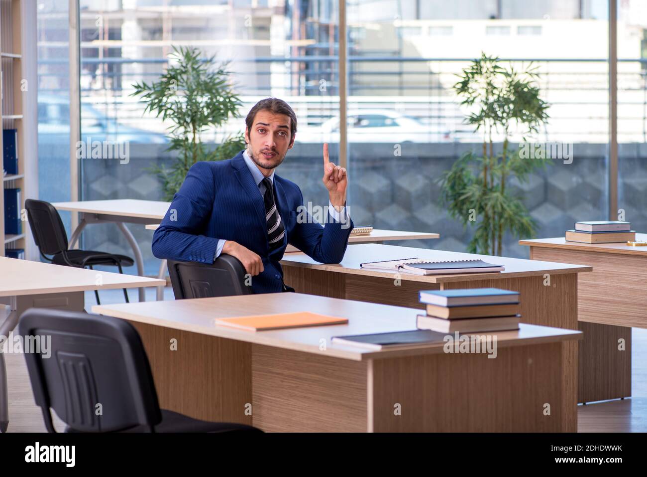 Young male teacher in suit in the classroom Stock Photo - Alamy