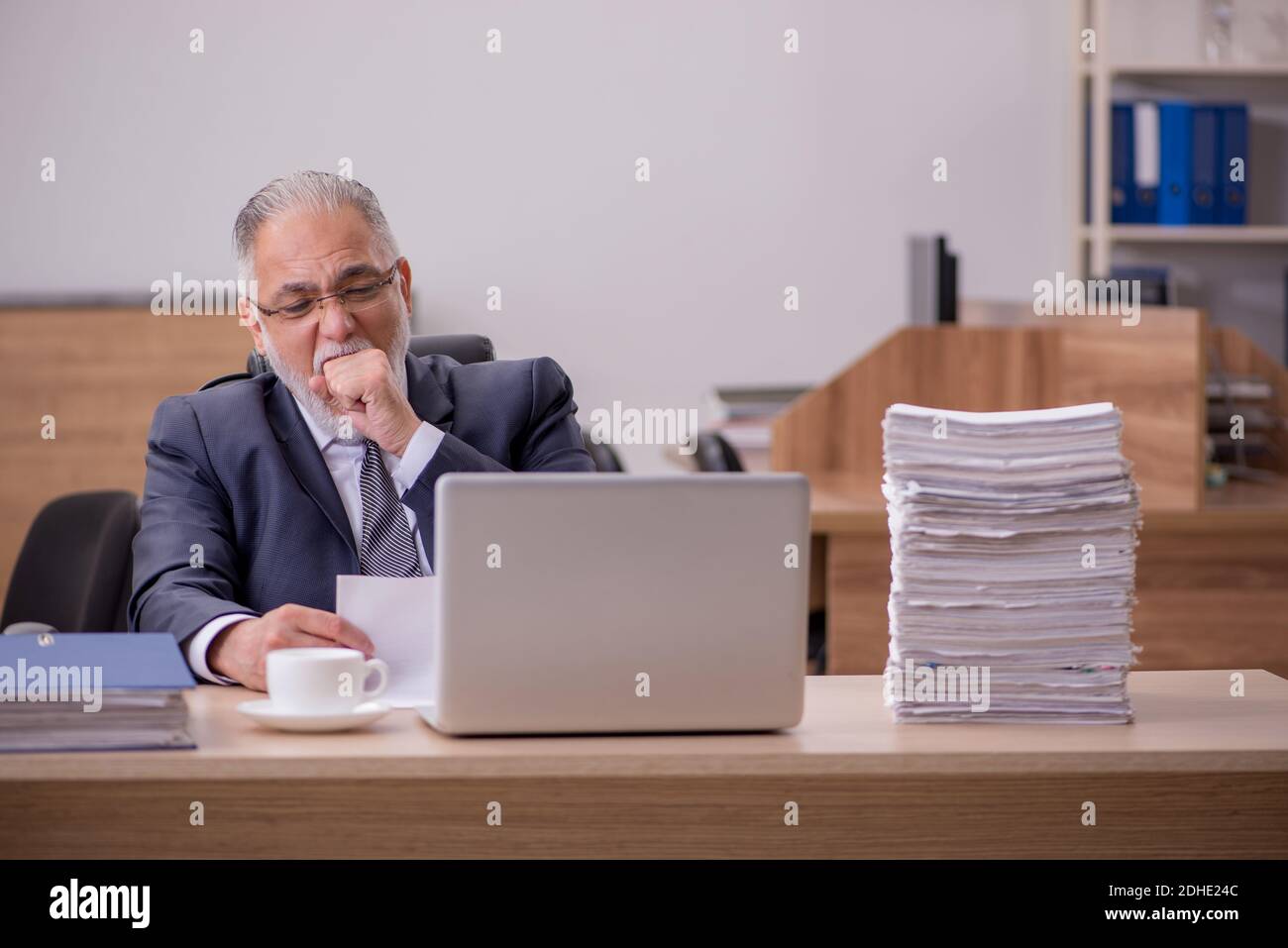 Old male employee reading paper in the office Stock Photo - Alamy