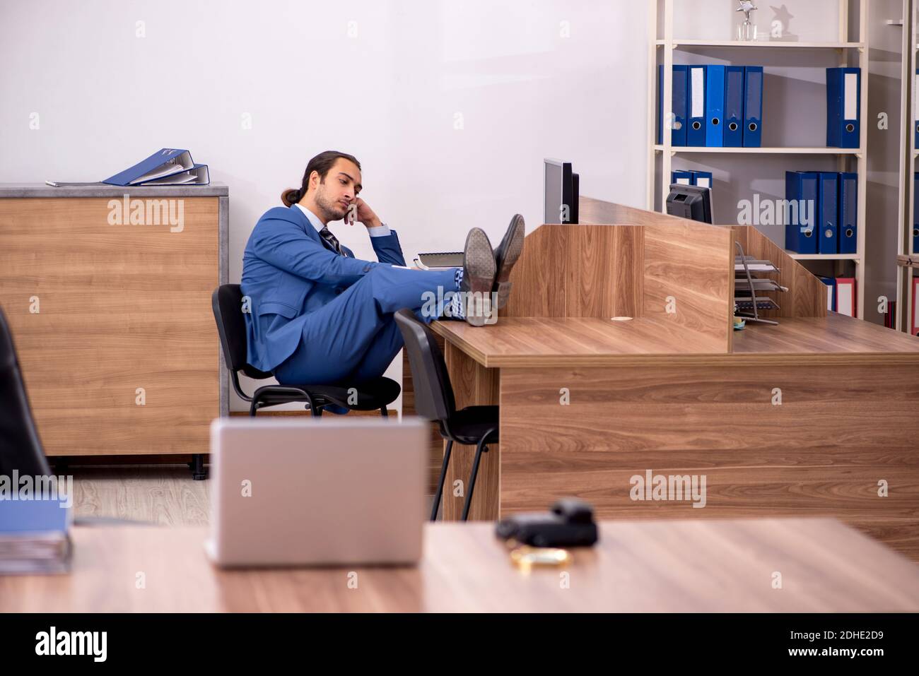 Young male employee sitting at workplace Stock Photo - Alamy