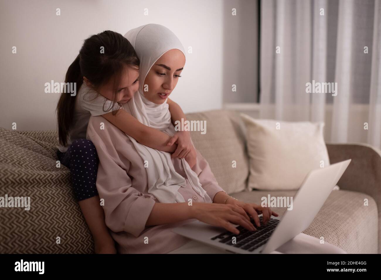 Muslim woman typing on laptop keyboard while working on remote project ...