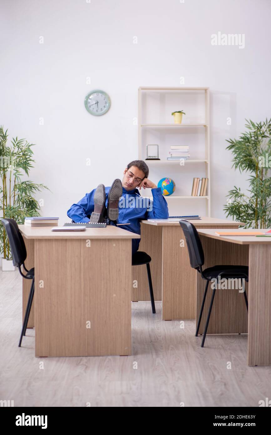 Young male teacher being tired in the classroom Stock Photo - Alamy