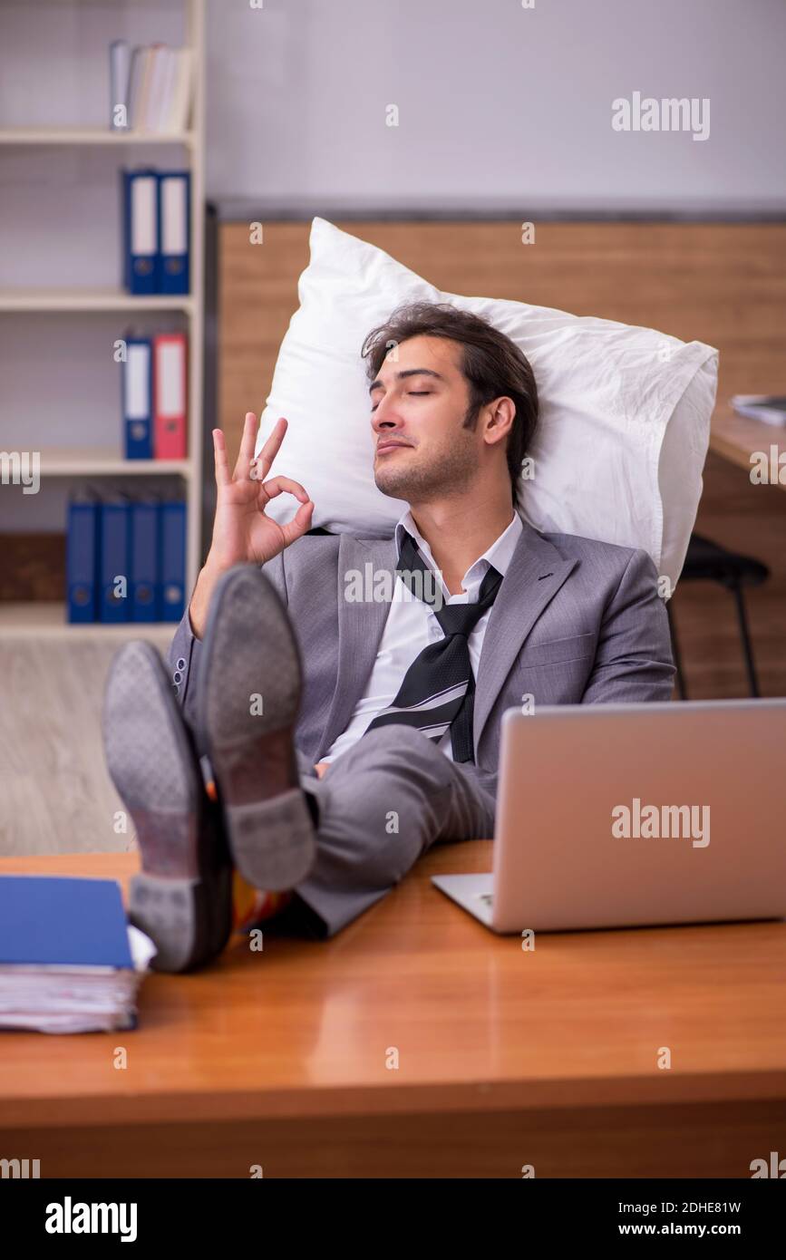 Young male employee sleeping at workplace Stock Photo - Alamy