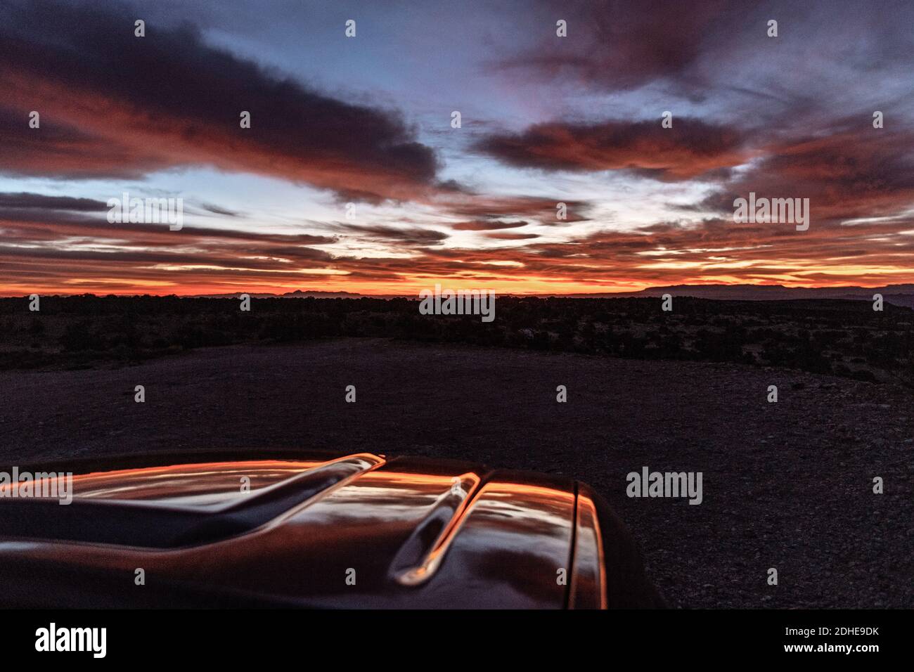 Vibrant desert sunrise reflected on hood of parked vehicle Stock Photo ...