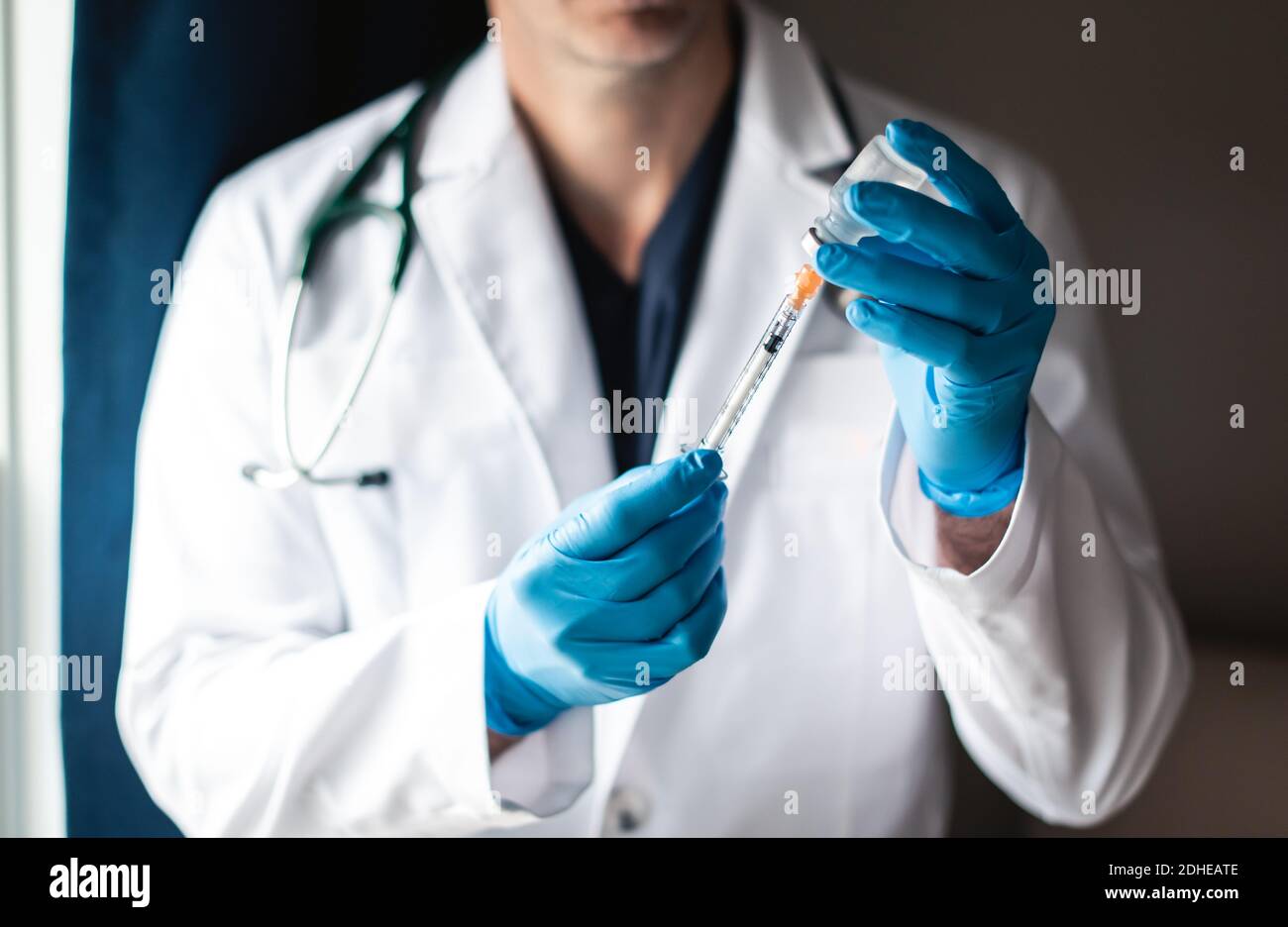 Doctor in white coat drawing vaccine into a syringe for injection Stock ...