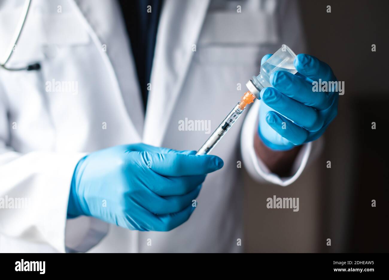 Doctor in white coat drawing vaccine into a syringe for injection Stock ...