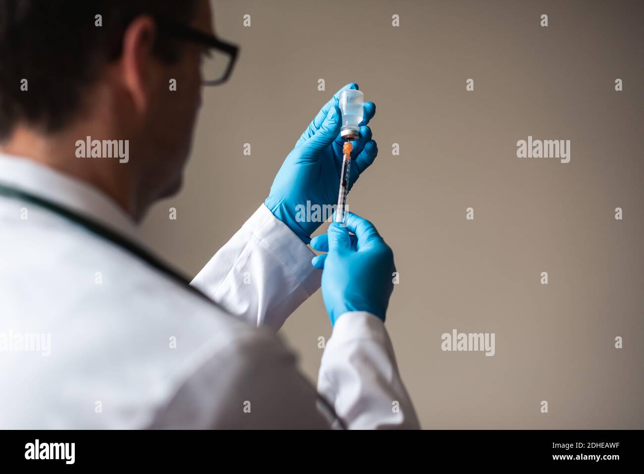 Doctor in white coat drawing vaccine into a syringe for injection Stock ...