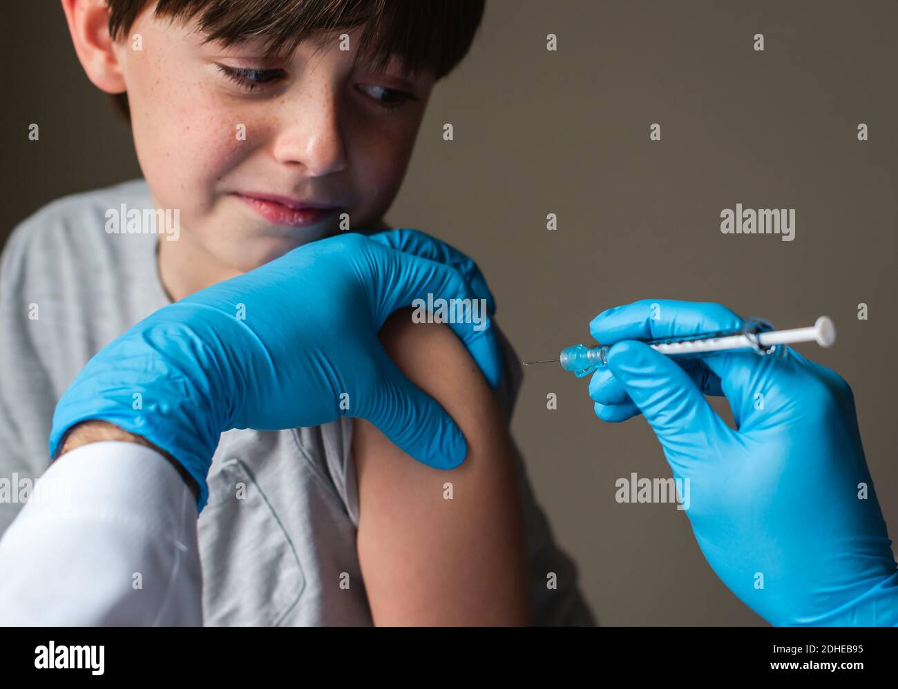 Nervous looking child getting vaccinated by doctor holding a needle ...