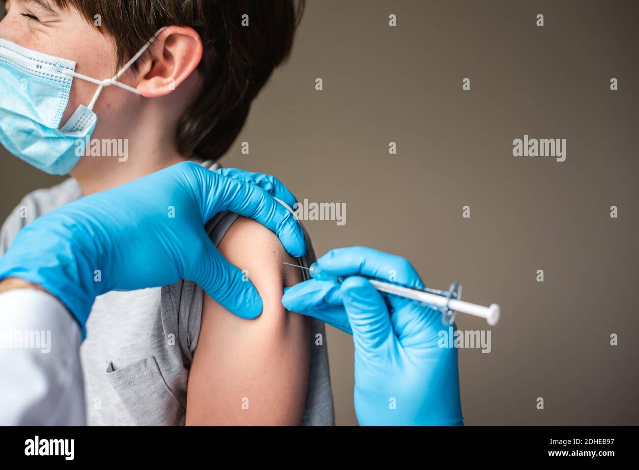 Child wearing mask getting vaccinated by doctor holding a needle Stock ...