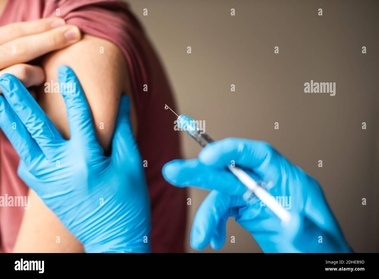 Close up of arm of boy getting vaccinated by doctor holding a needle ...