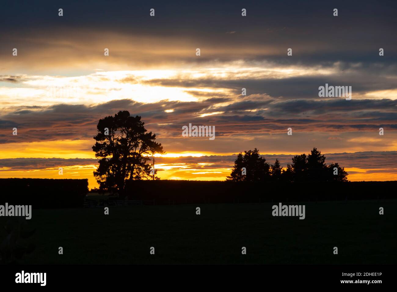 Bright sun sets over distant horizon behind silhouete landscape and a ...