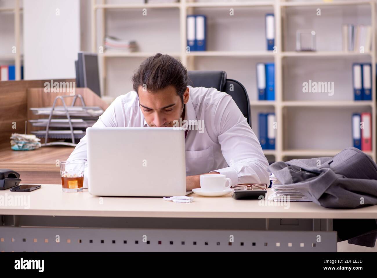 Young male employee drinking alcohol in the office Stock Photo - Alamy