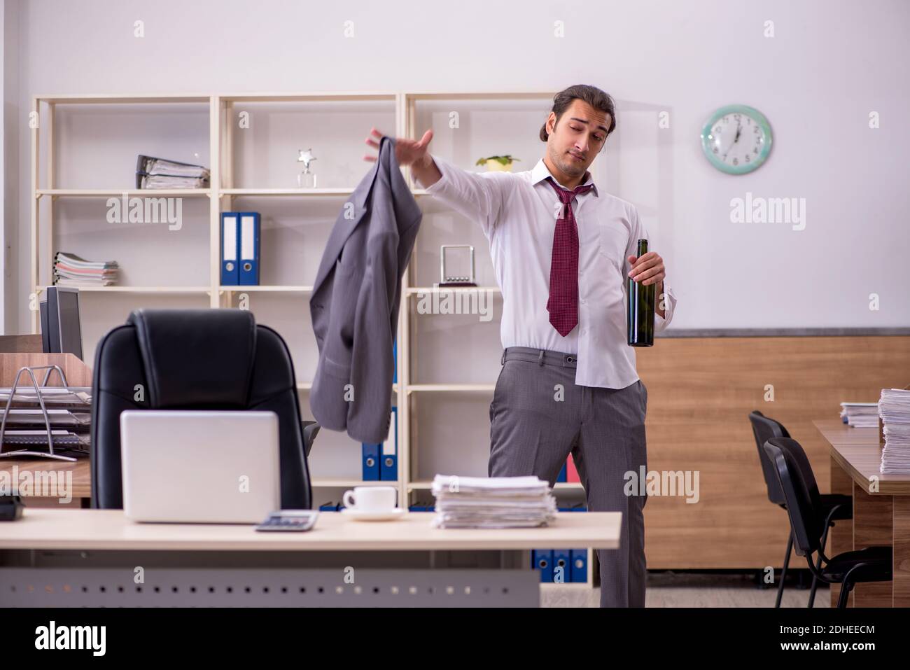 Young male employee drinking alcohol in the office Stock Photo - Alamy