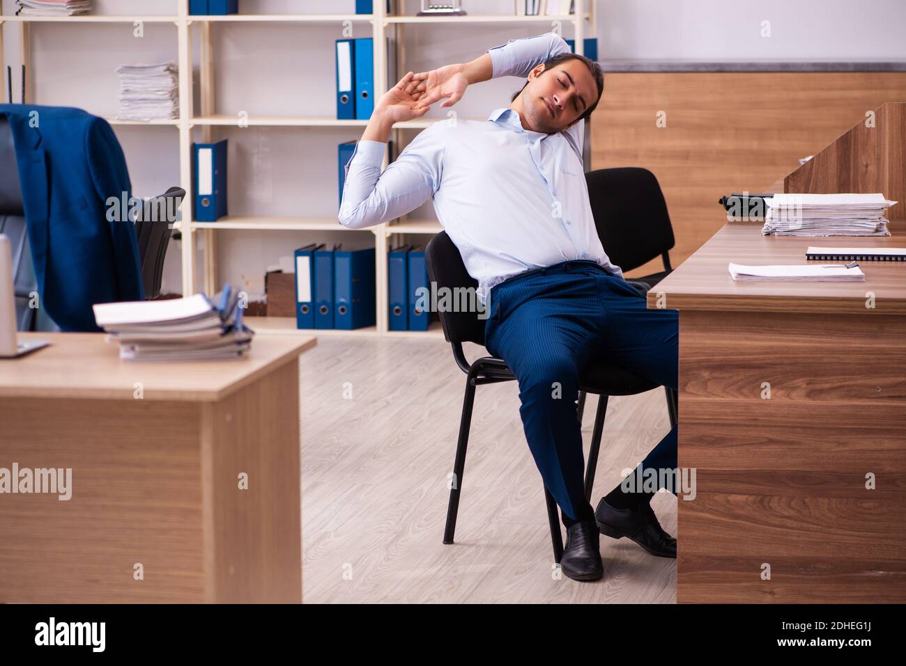 Young male employee stretching at workplace Stock Photo - Alamy