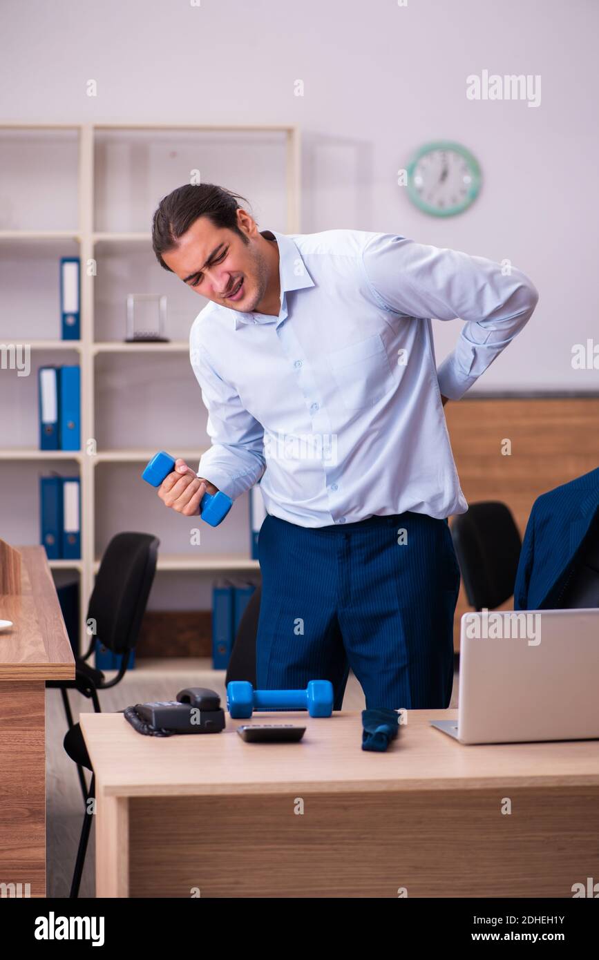 Young male employee doing physical exercises at workplace Stock Photo ...