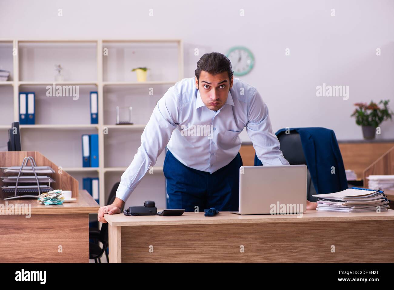 Young male employee suffering at workplace Stock Photo - Alamy