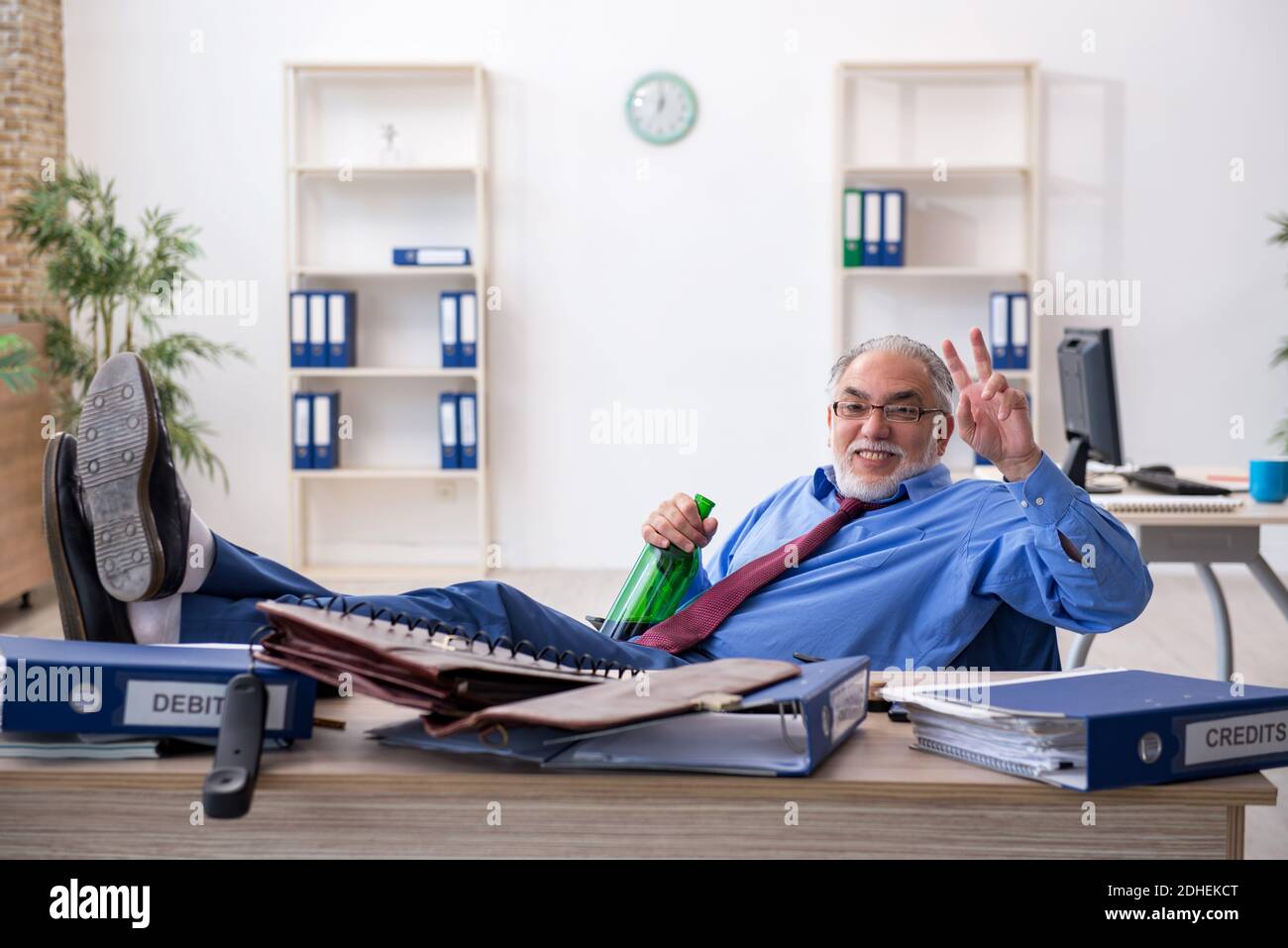 Old male employee drinking alcohol in the office Stock Photo - Alamy