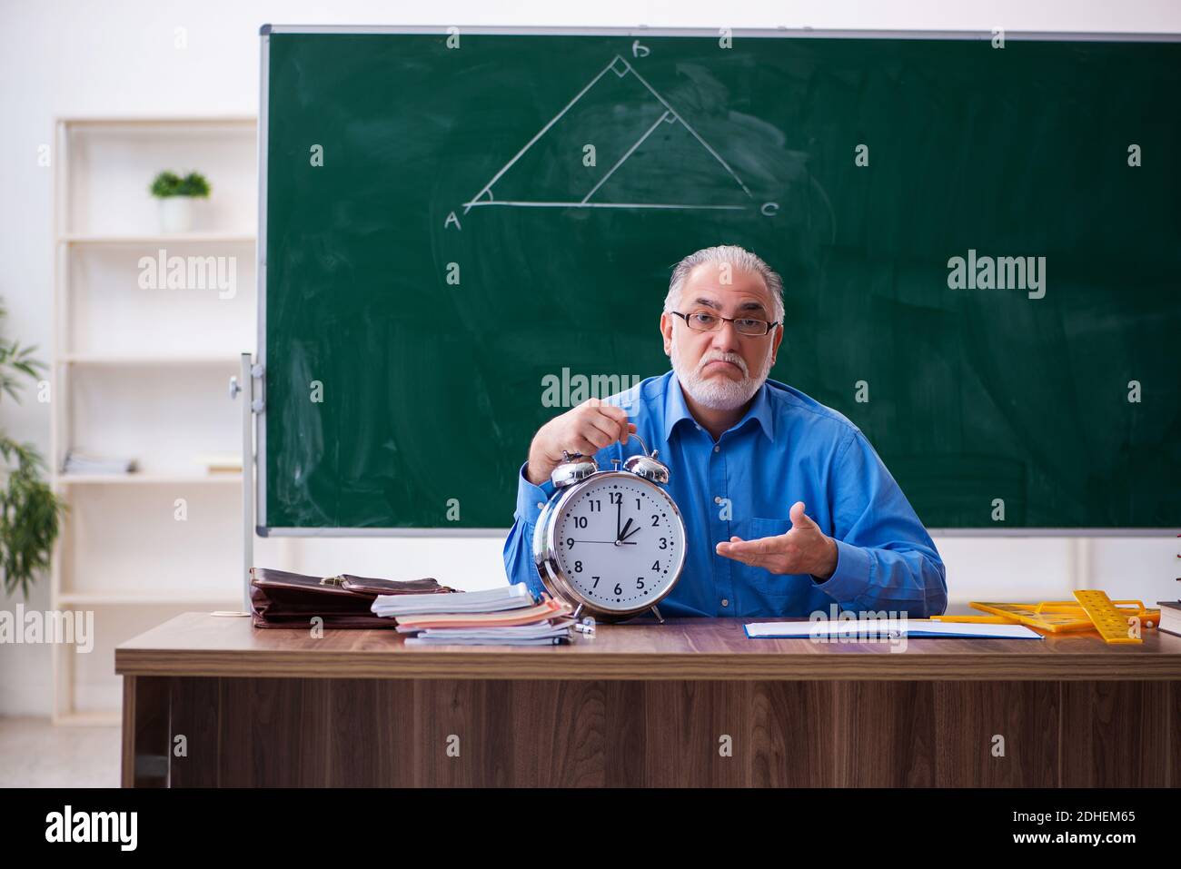 Old male math teacher in time management concept Stock Photo - Alamy