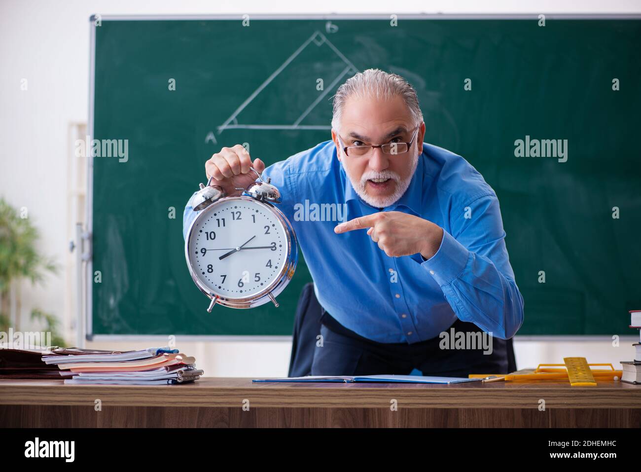 Old male math teacher in time management concept Stock Photo - Alamy