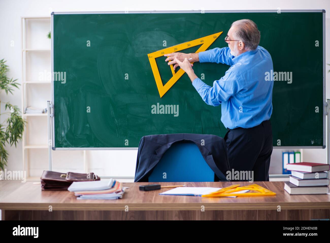 Old male geometry teacher holding triangle Stock Photo - Alamy