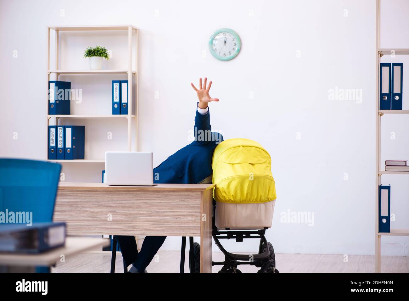 Young male employee looking after kid at workplace Stock Photo - Alamy
