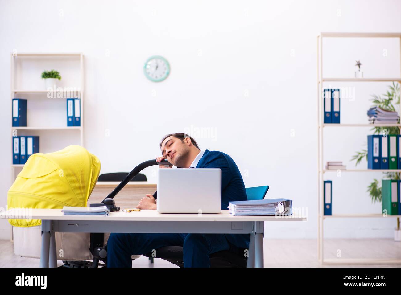 Young male employee looking after kid at workplace Stock Photo - Alamy