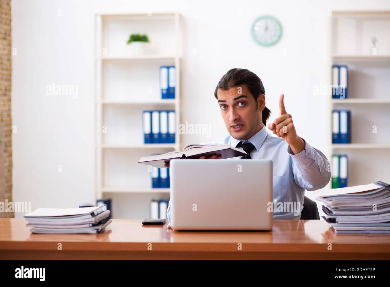 Young male student employee reading book at workplace Stock Photo - Alamy