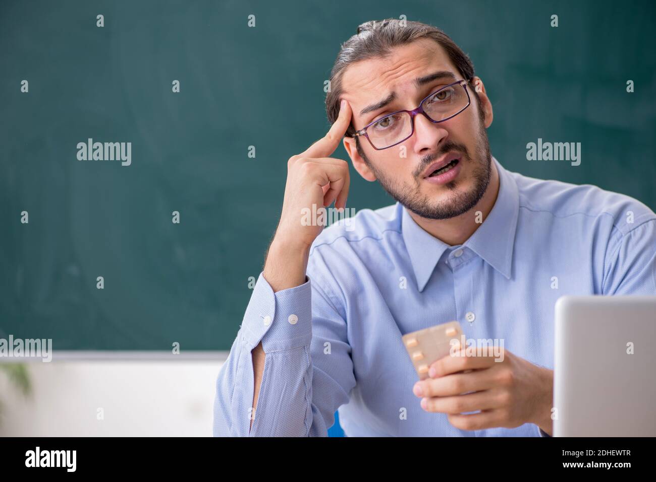 Young sick male teacher in the classroom Stock Photo - Alamy
