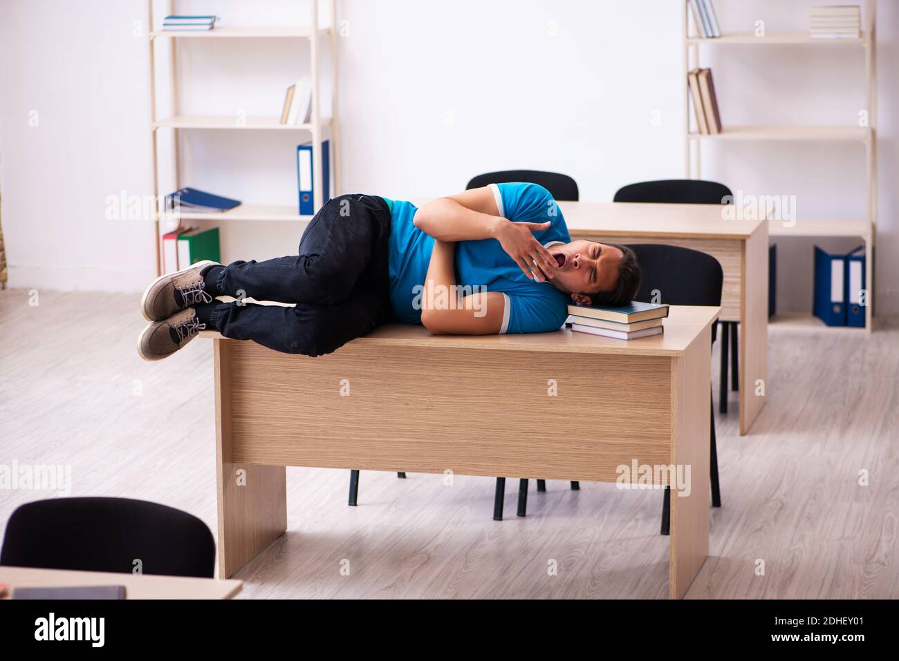 Exhausted male student preparing for the exams in the classroom Stock ...