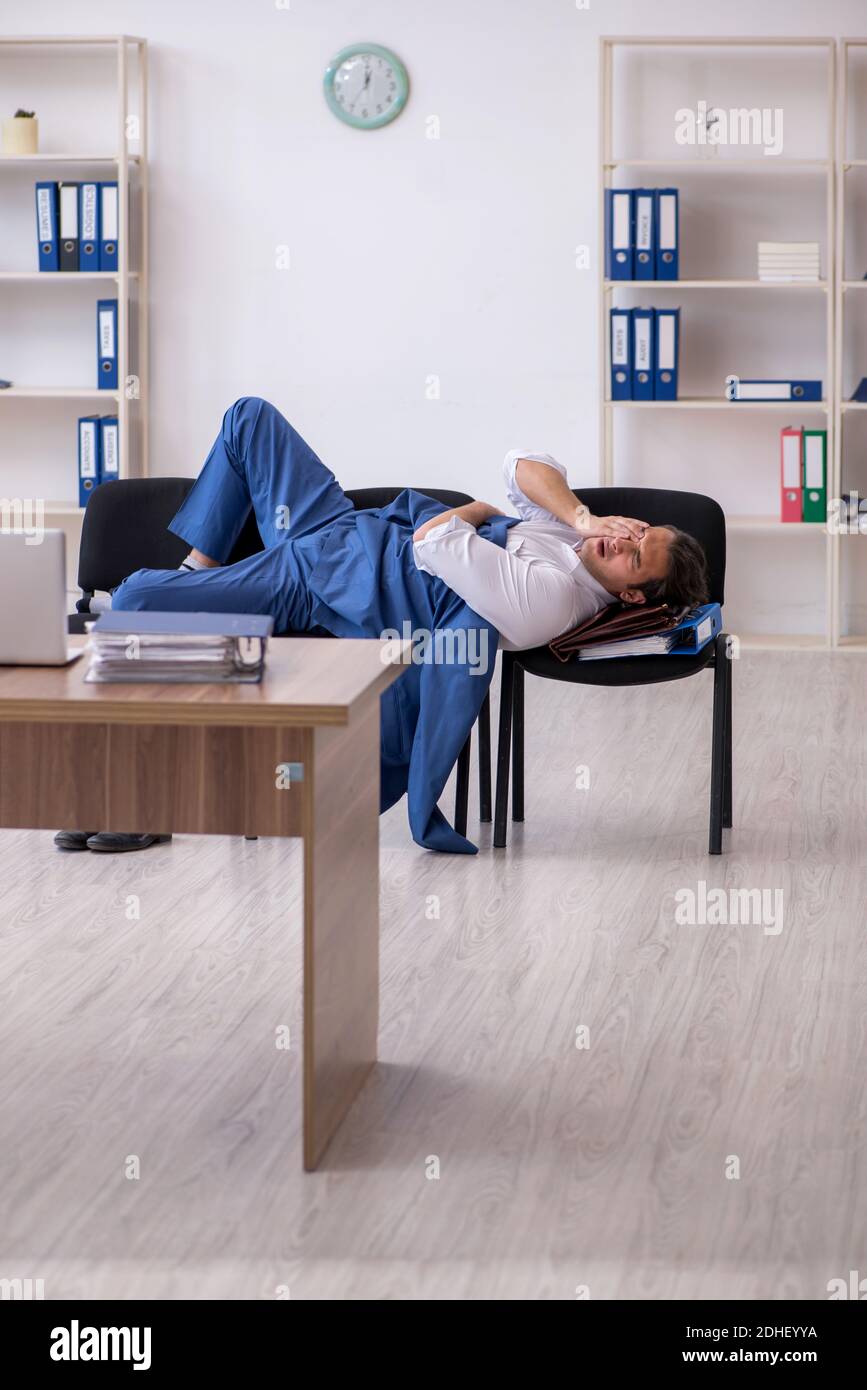 Young male employee sleeping in the office on chairs Stock Photo - Alamy