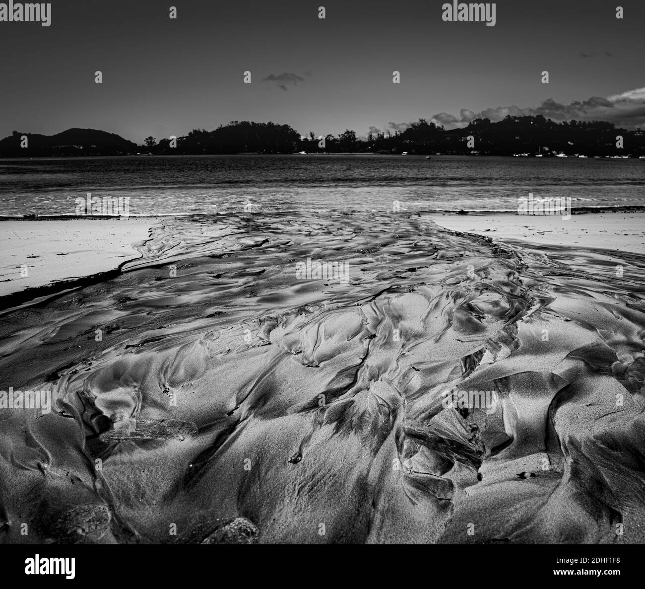 Patterns in created by water from small stream washing across beach to ...