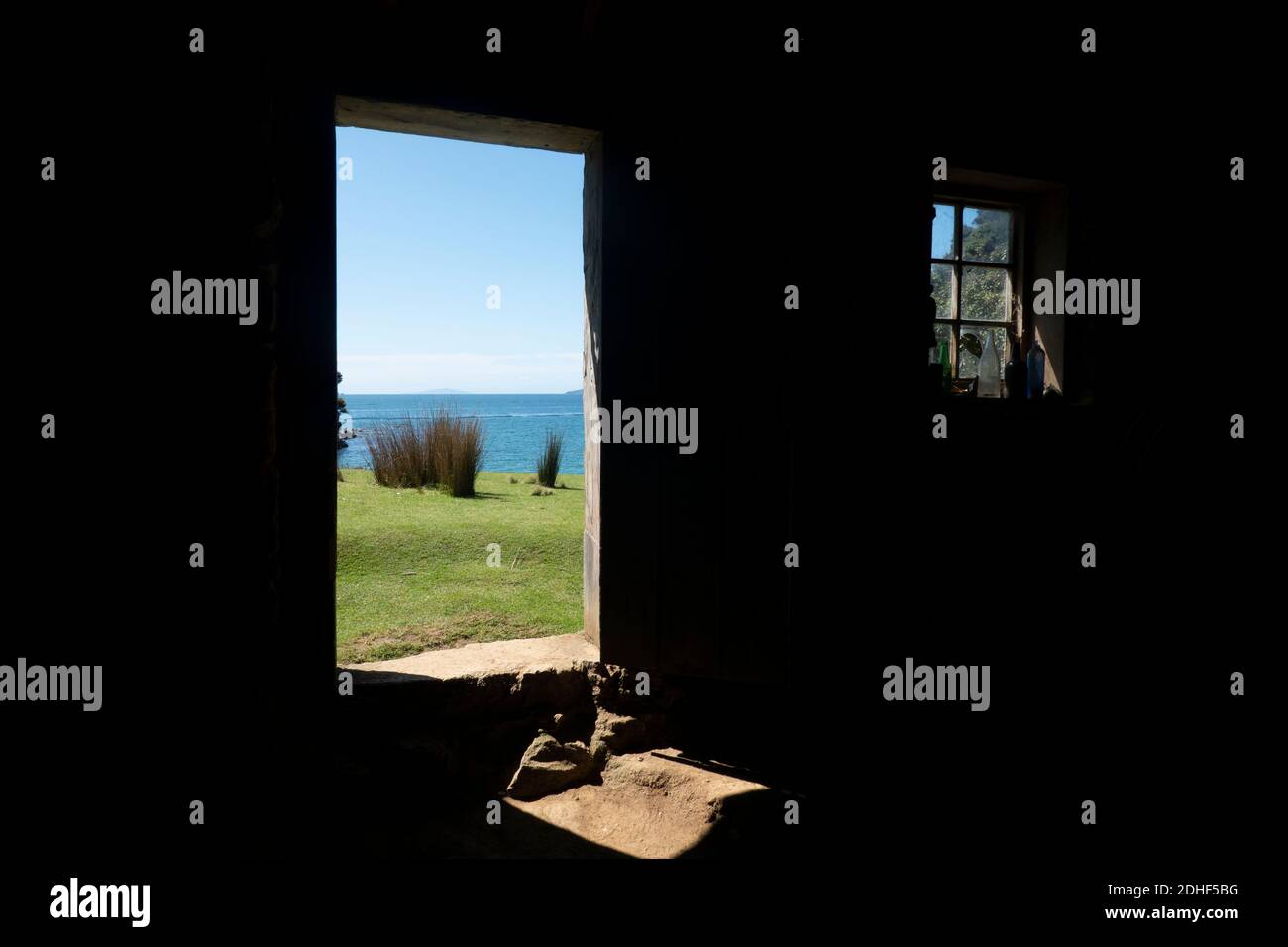 View through open door and broken window of old stone shack Stock Photo ...