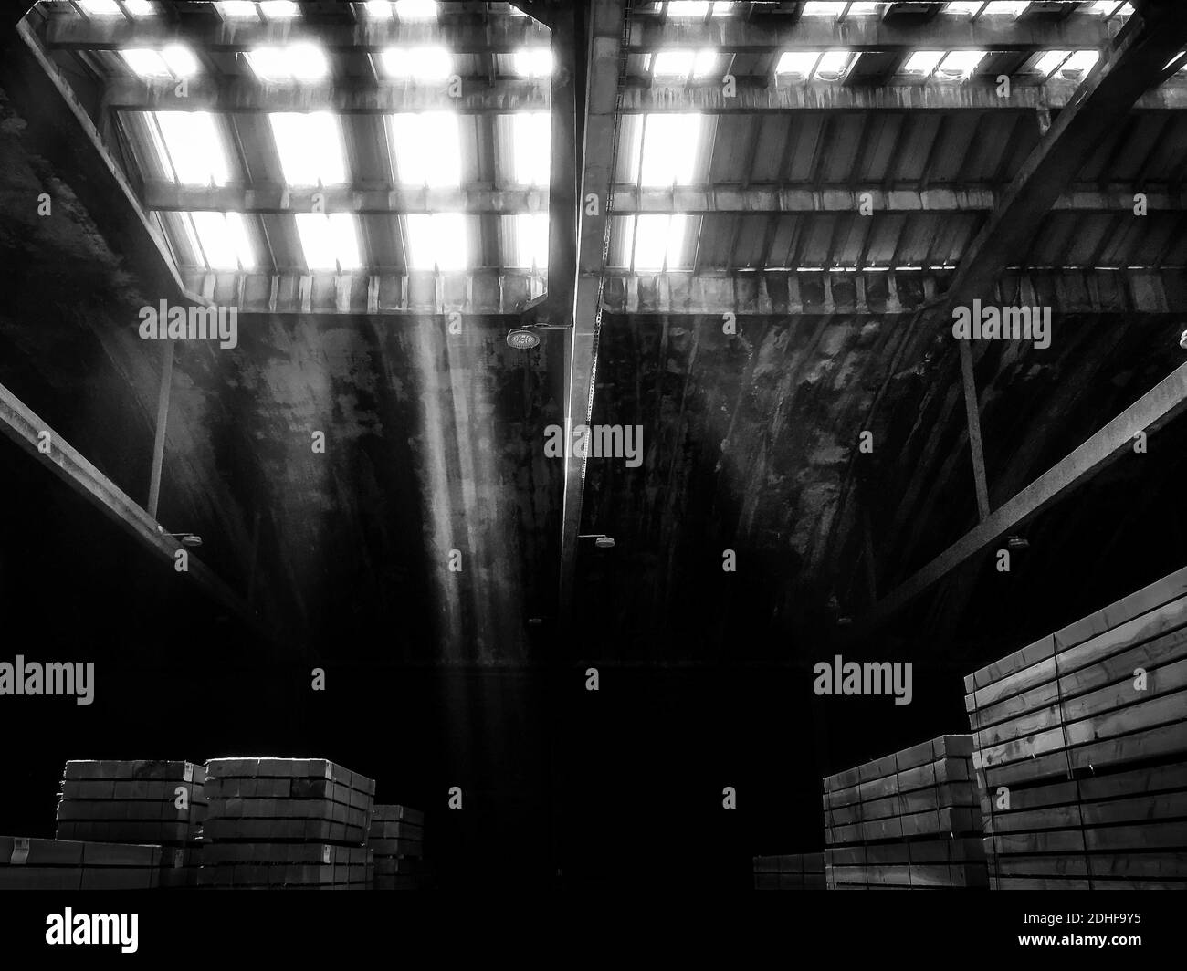 A grayscale shot of an old wooden building with the sun rays breaking ...