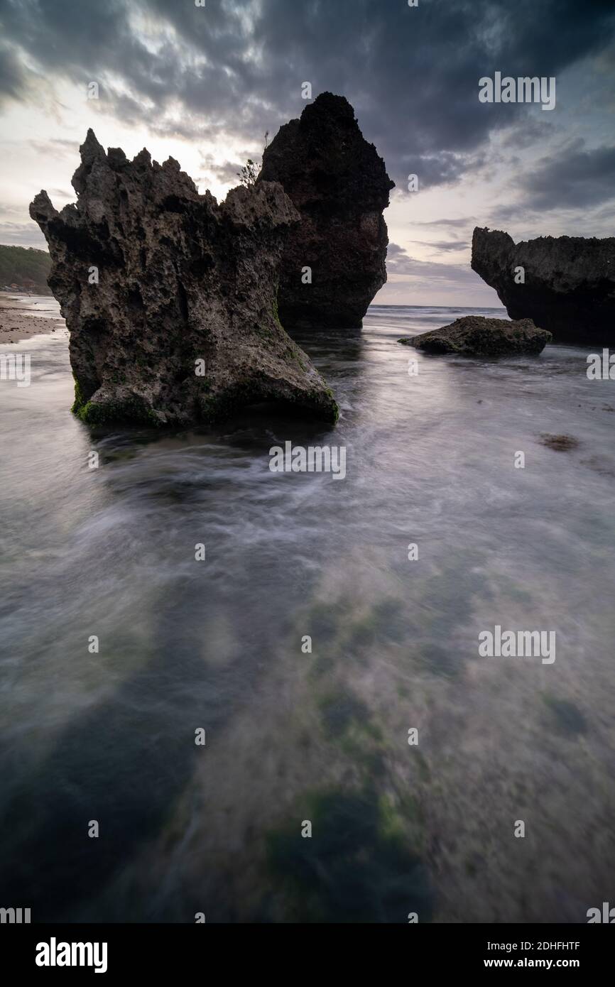 A vertical shot of rocks in a sea on background of the gloomy sky ...