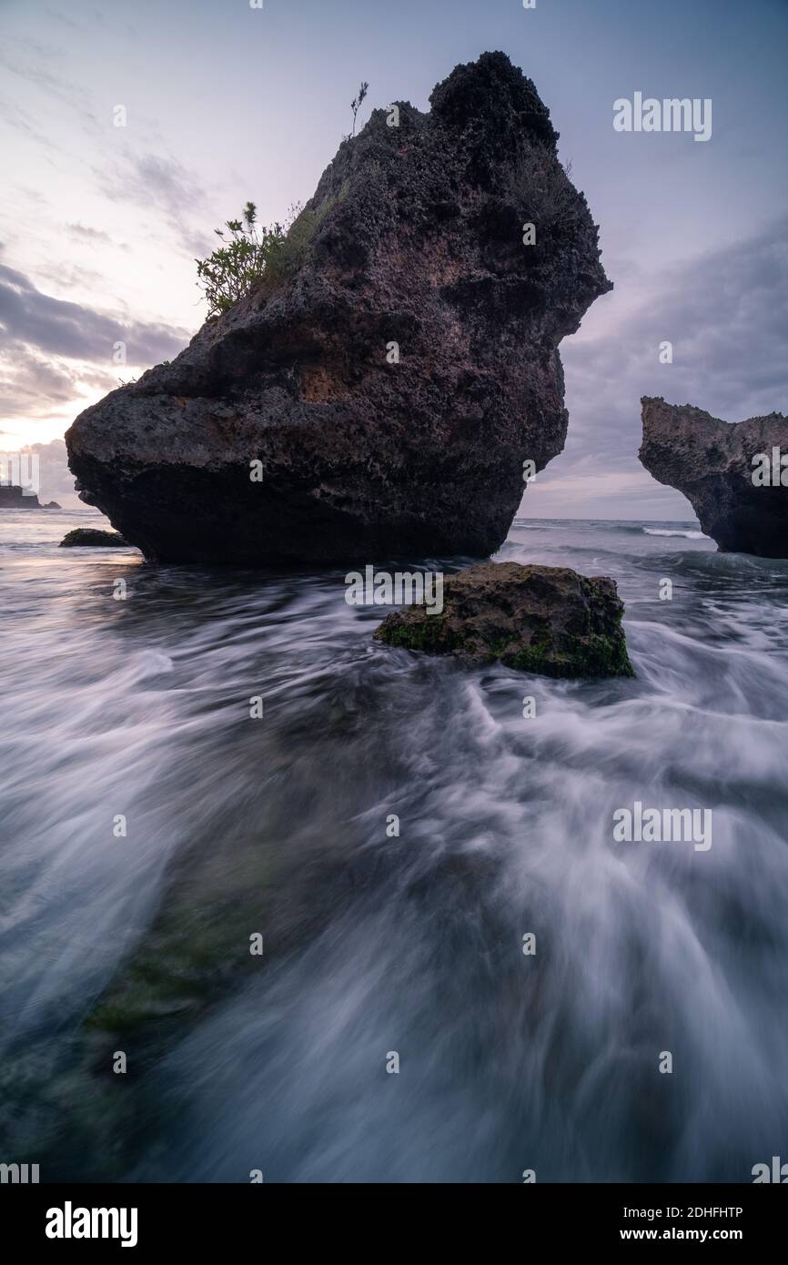 A vertical shot of rocks in a sea on background of the gloomy sky ...