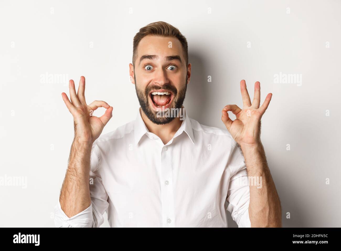 Close-up of amazed caucasian guy agreeing, showing okay signs and ...