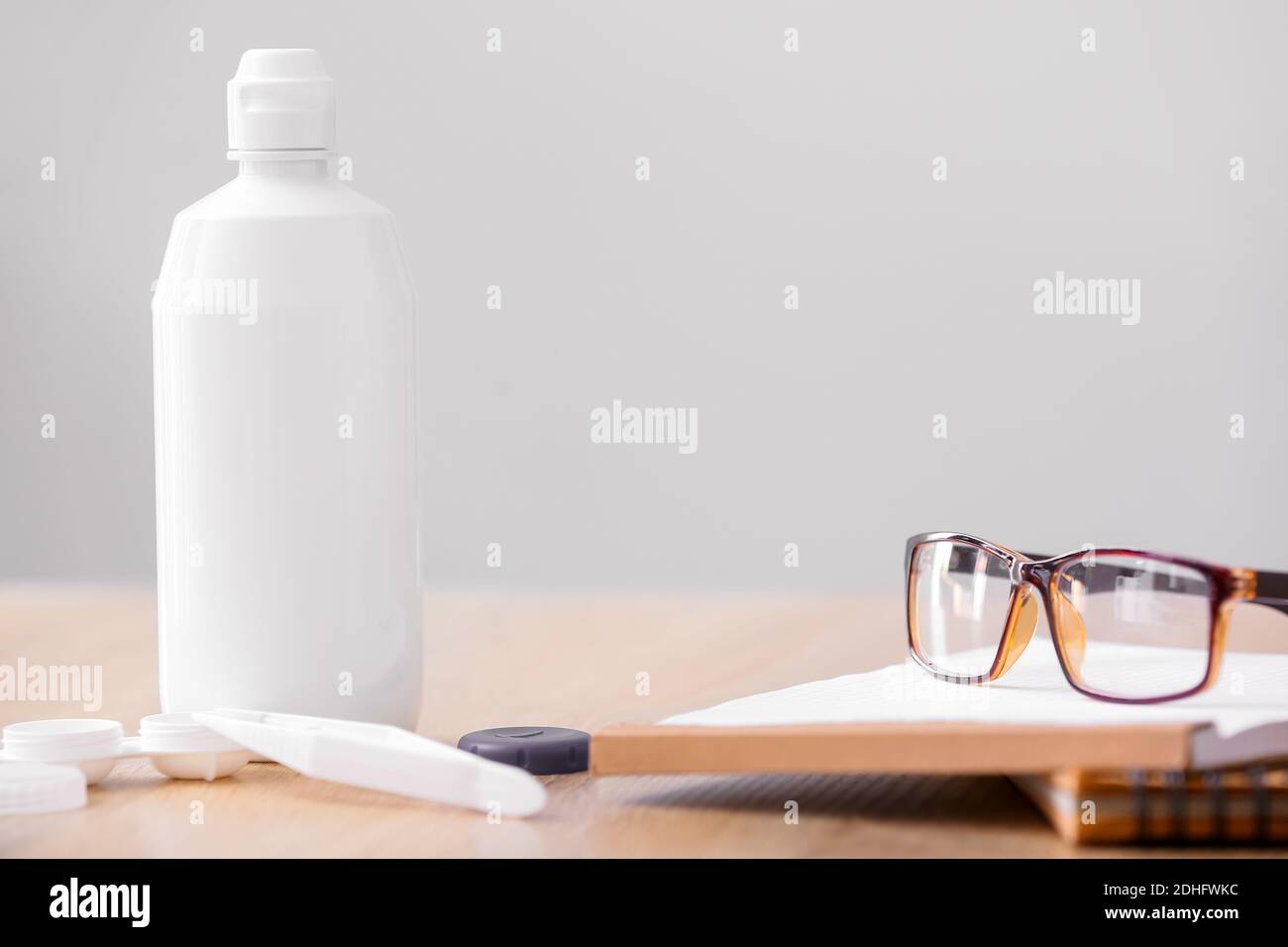 Container with contact lenses, solution, eyeglasses and tweezers on ...