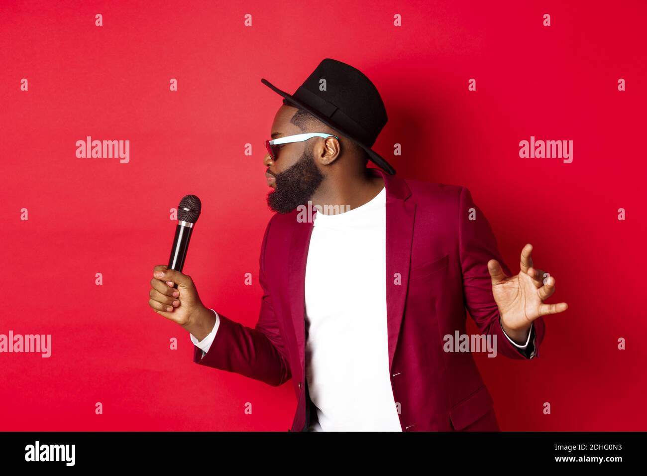 Passionate black male singer performing against red background, singing ...