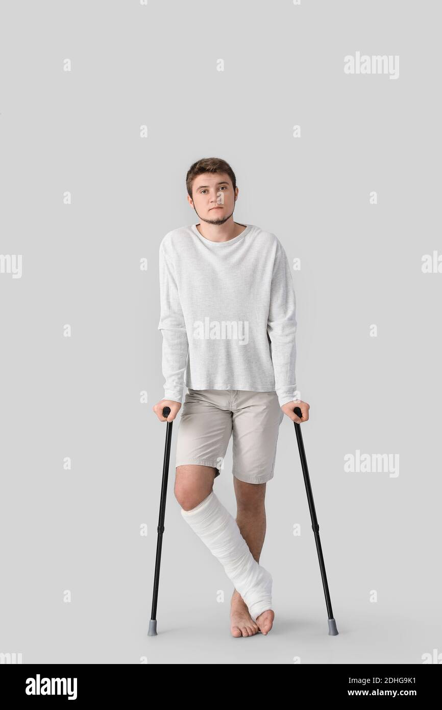 Young man with broken leg on grey background Stock Photo - Alamy