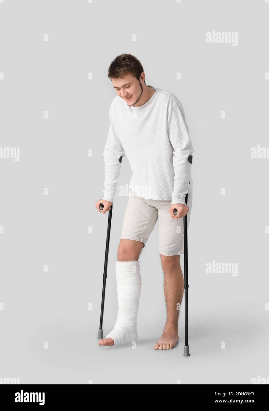 Young man with broken leg on grey background Stock Photo - Alamy