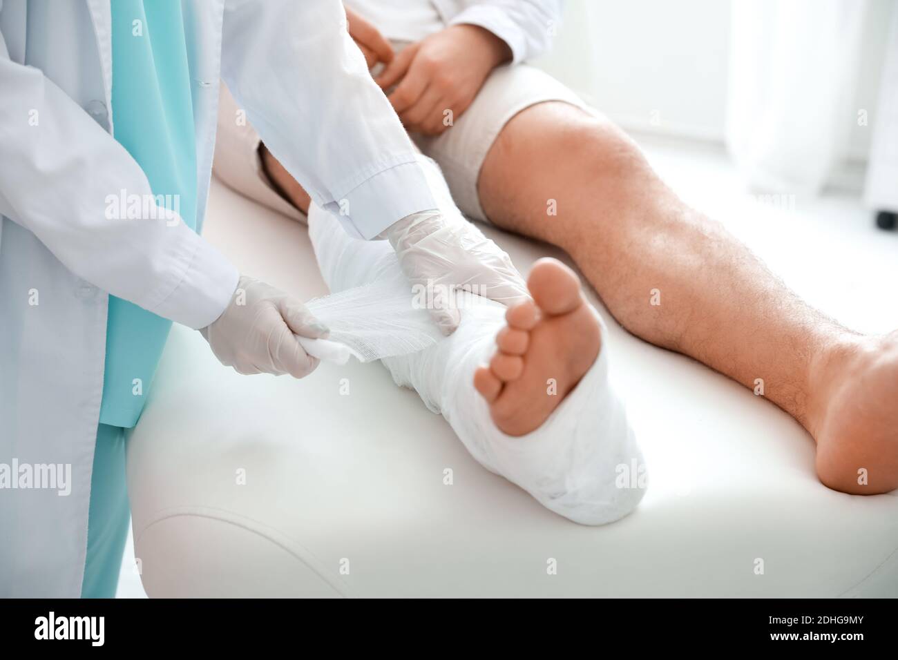 Doctor putting broken leg of young man in plaster Stock Photo - Alamy